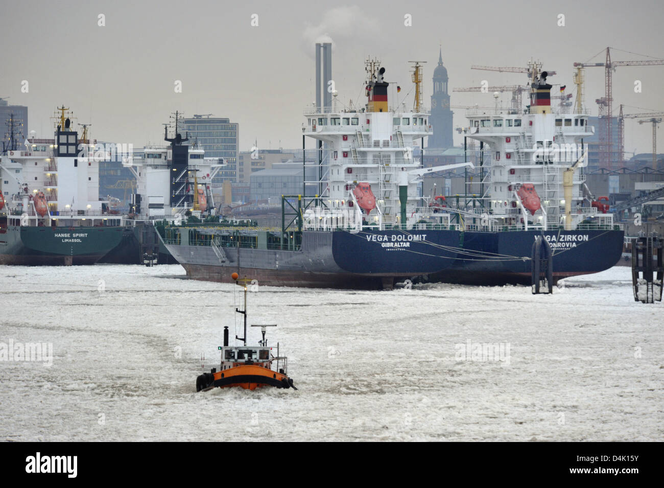 Empty container freighters lie at harbour on the icy river Elbe while a ...