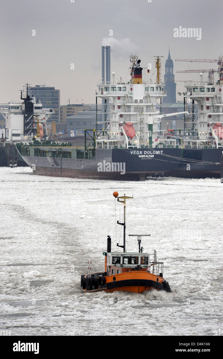 Empty container freighters lie at harbour on the icy river Elbe while a ...