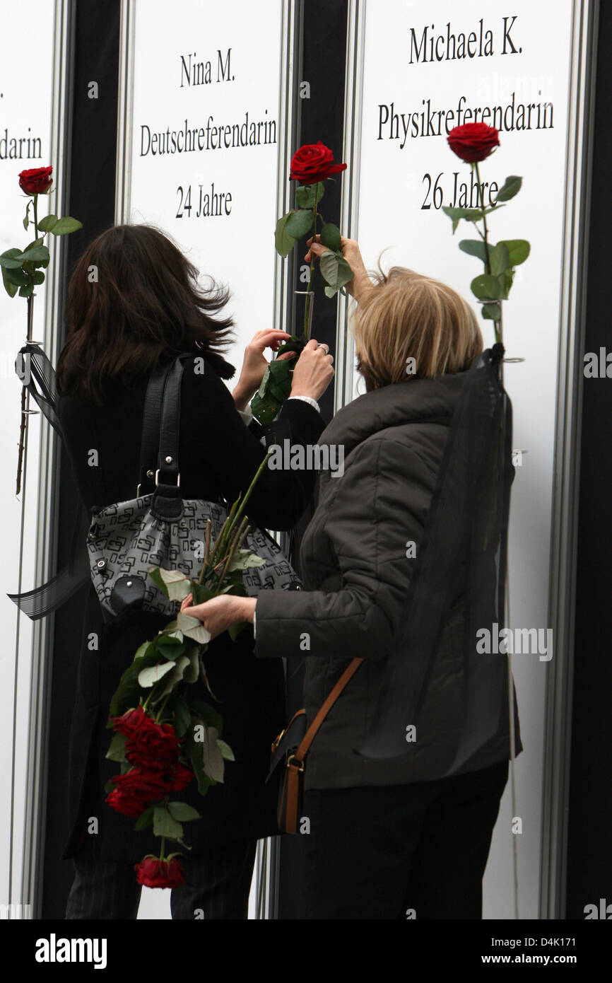 Two women attach roses to mourning plaques for the victims of the ...