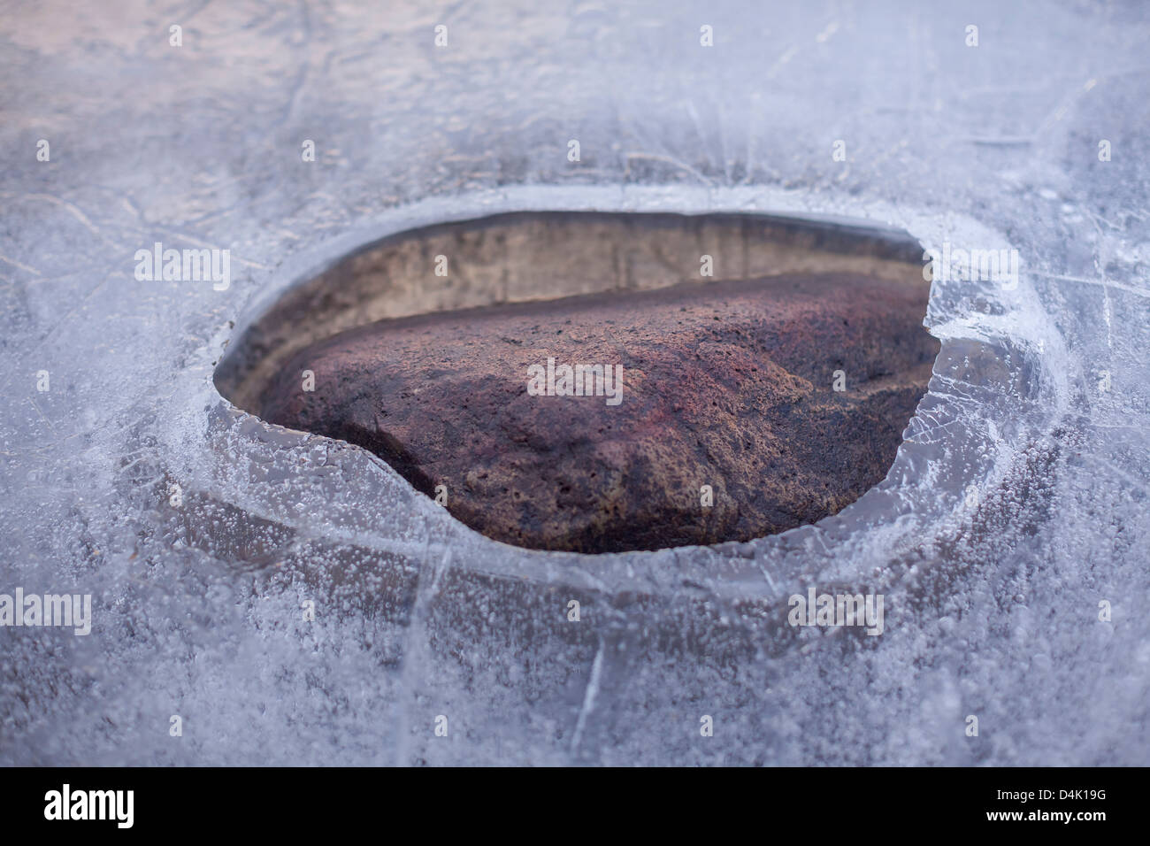 Hole in layer of ice on rural lake Stock Photo - Alamy