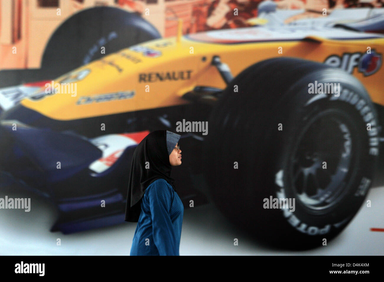 A Malaysian woman passes an advertising banner of the Formula One Grand ...