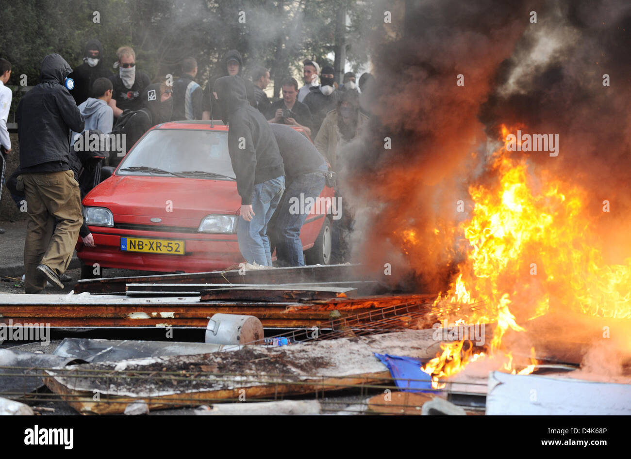 Hooded protestors riot next to burning barricades on a street in ...