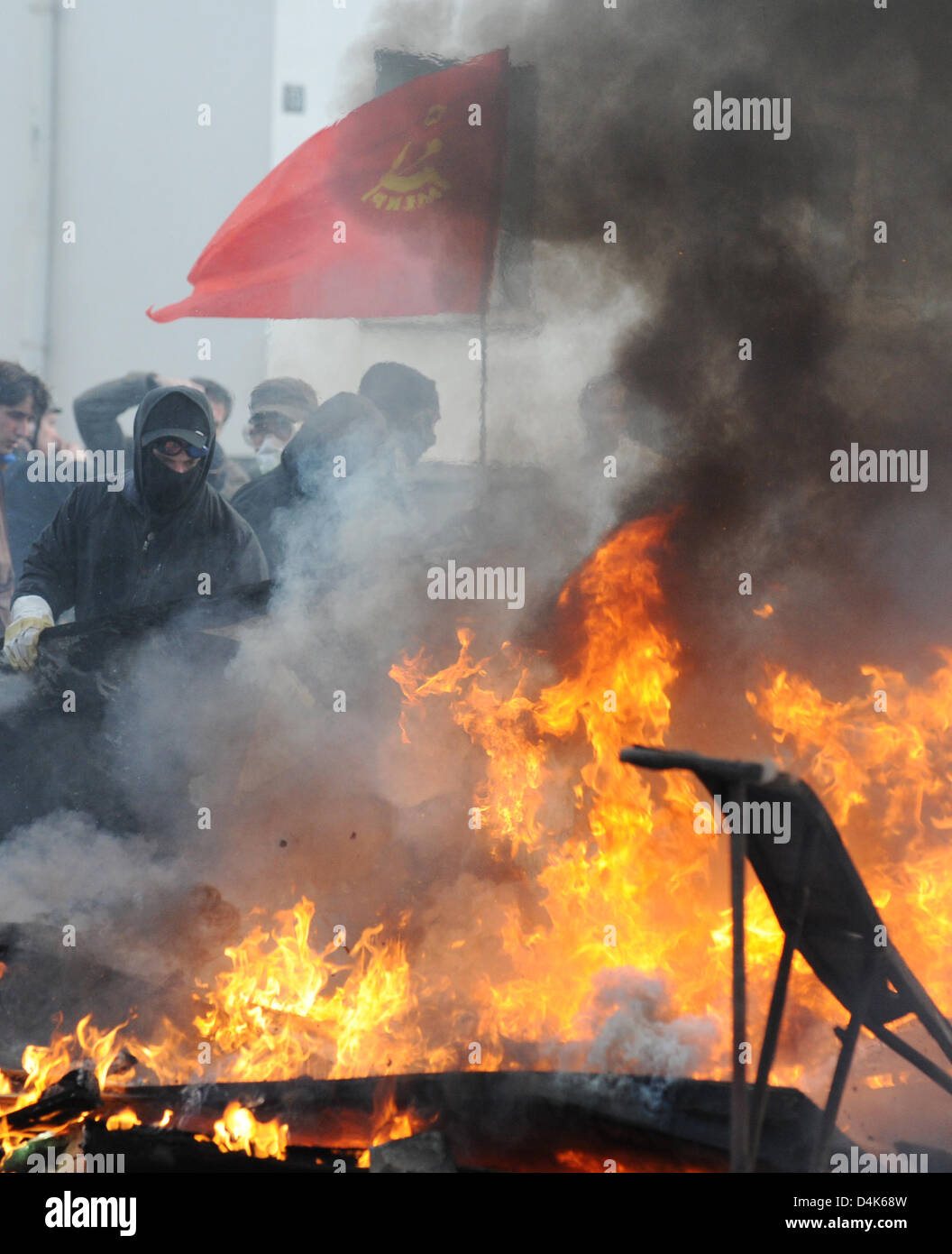 Hooded protestors riot next to burning barricades on a street in ...