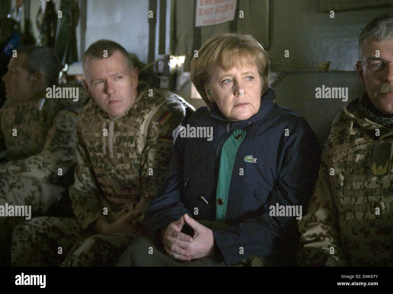German Chancellor Angela Merkel (C) sits between officers in a ...