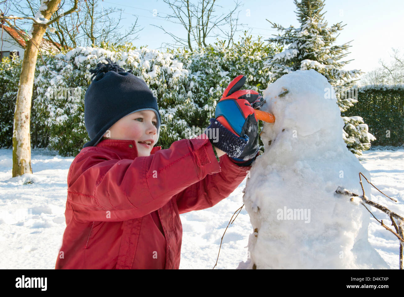 Boy making snowman in garden Stock Photo - Alamy
