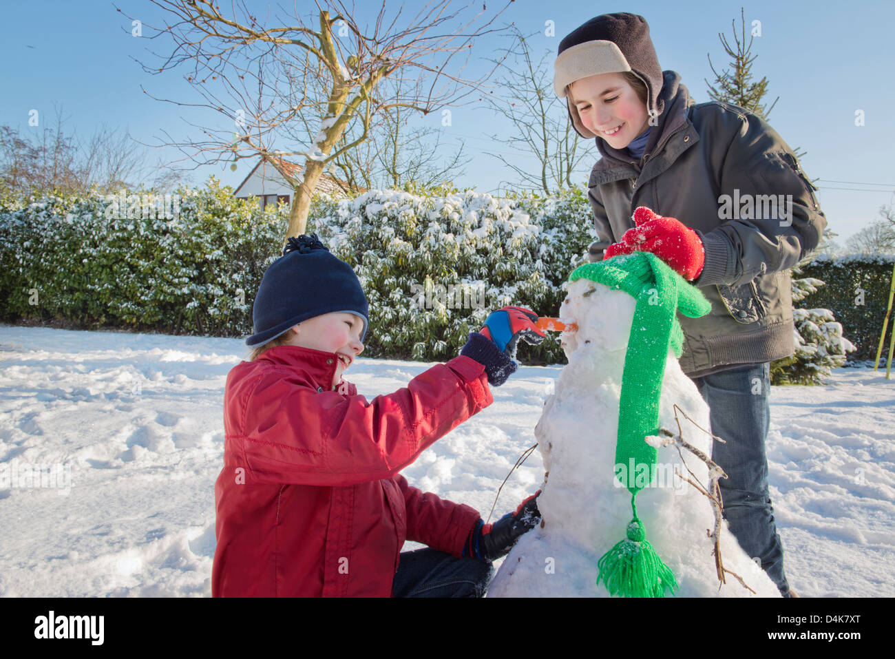 Boys making snowman in garden Stock Photo - Alamy