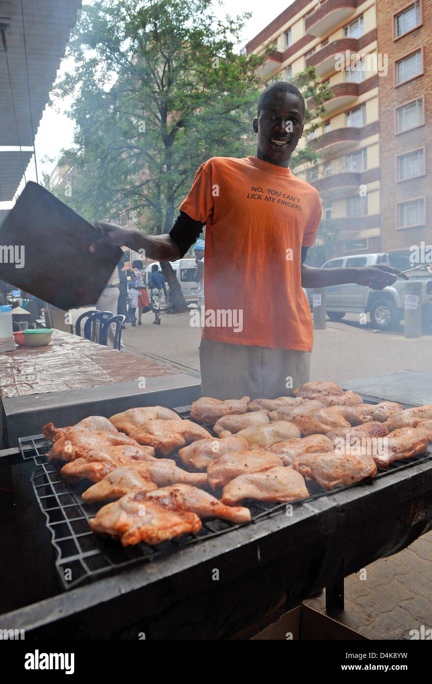 A street vendor grills chicken legs on a market in the borough Hillbrow ...