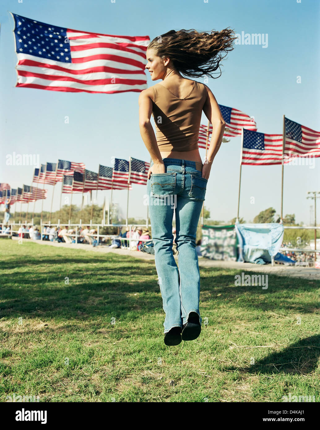 Woman jumping in field of US flags Stock Photo - Alamy