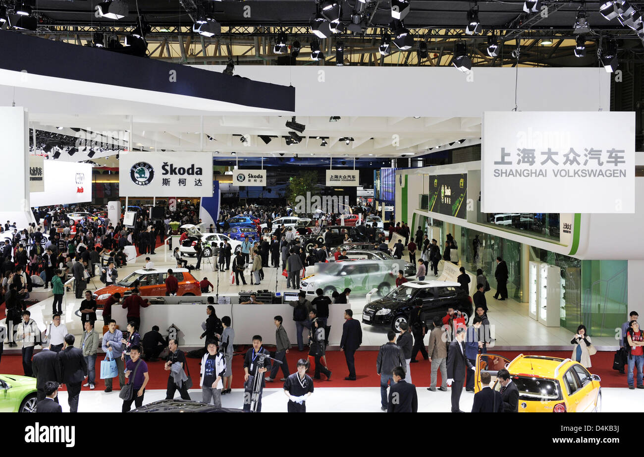 Visitors examine the cars on the press day of the Shanghai Auto Show ...