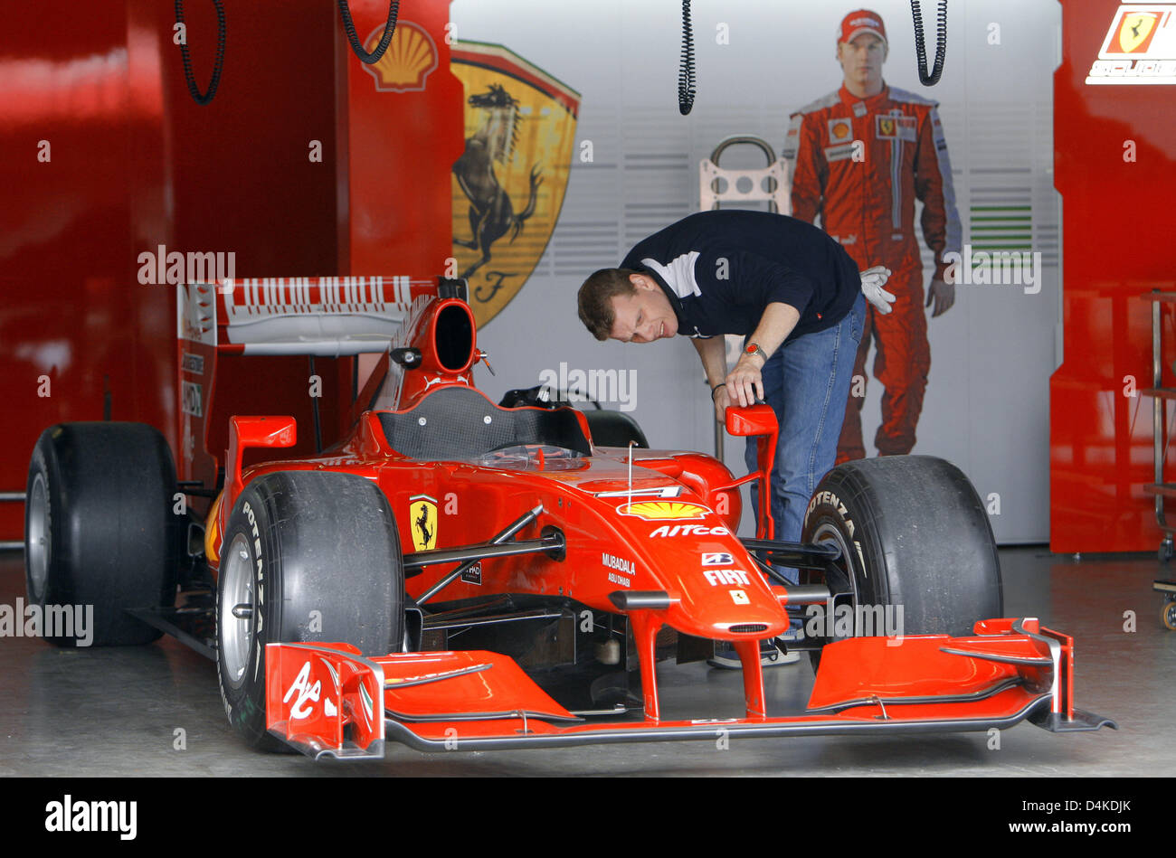 A man takes a look at a Ferrari racing car in the team?s garage at ...