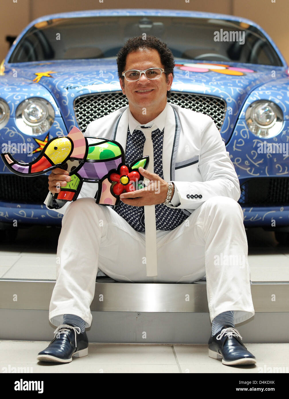Brazilian artist Romero Britto holds one of his sculptures in front of ...
