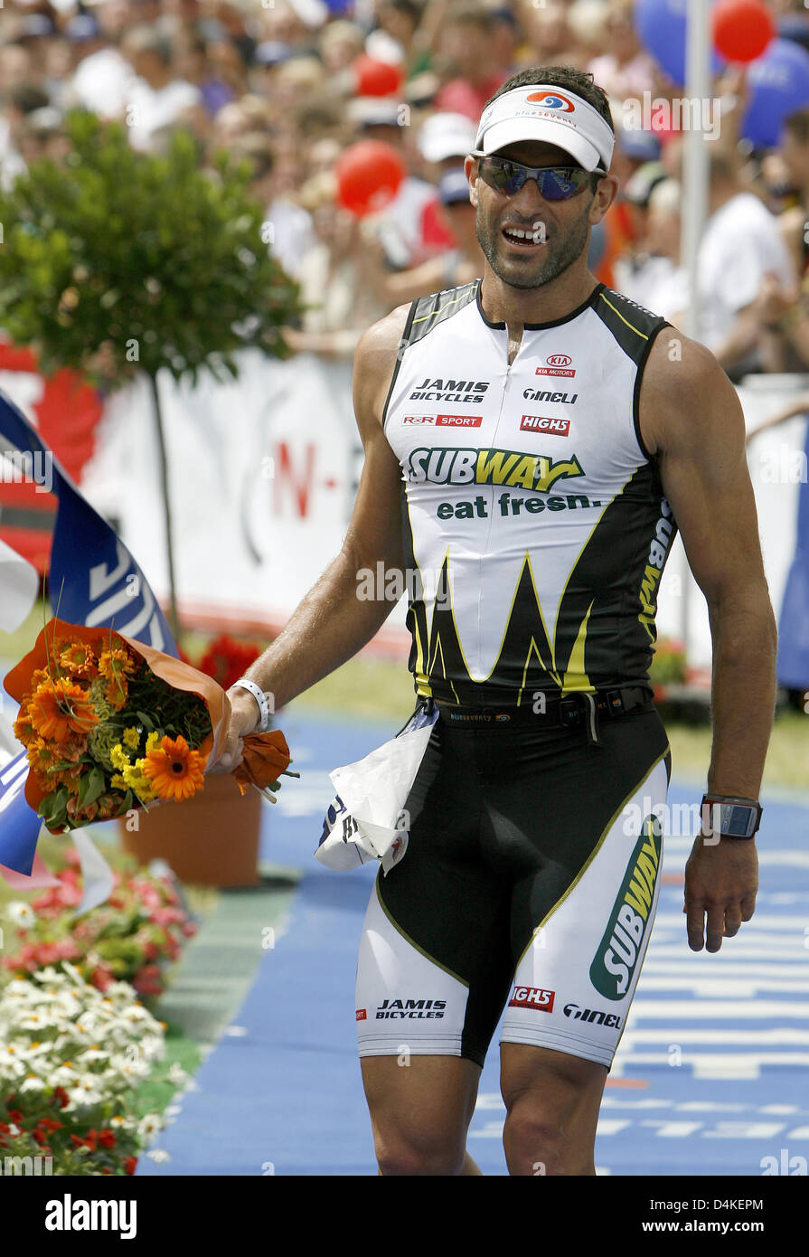 Triathlete Richard Usher from New Zealand crosses the finish line of ...