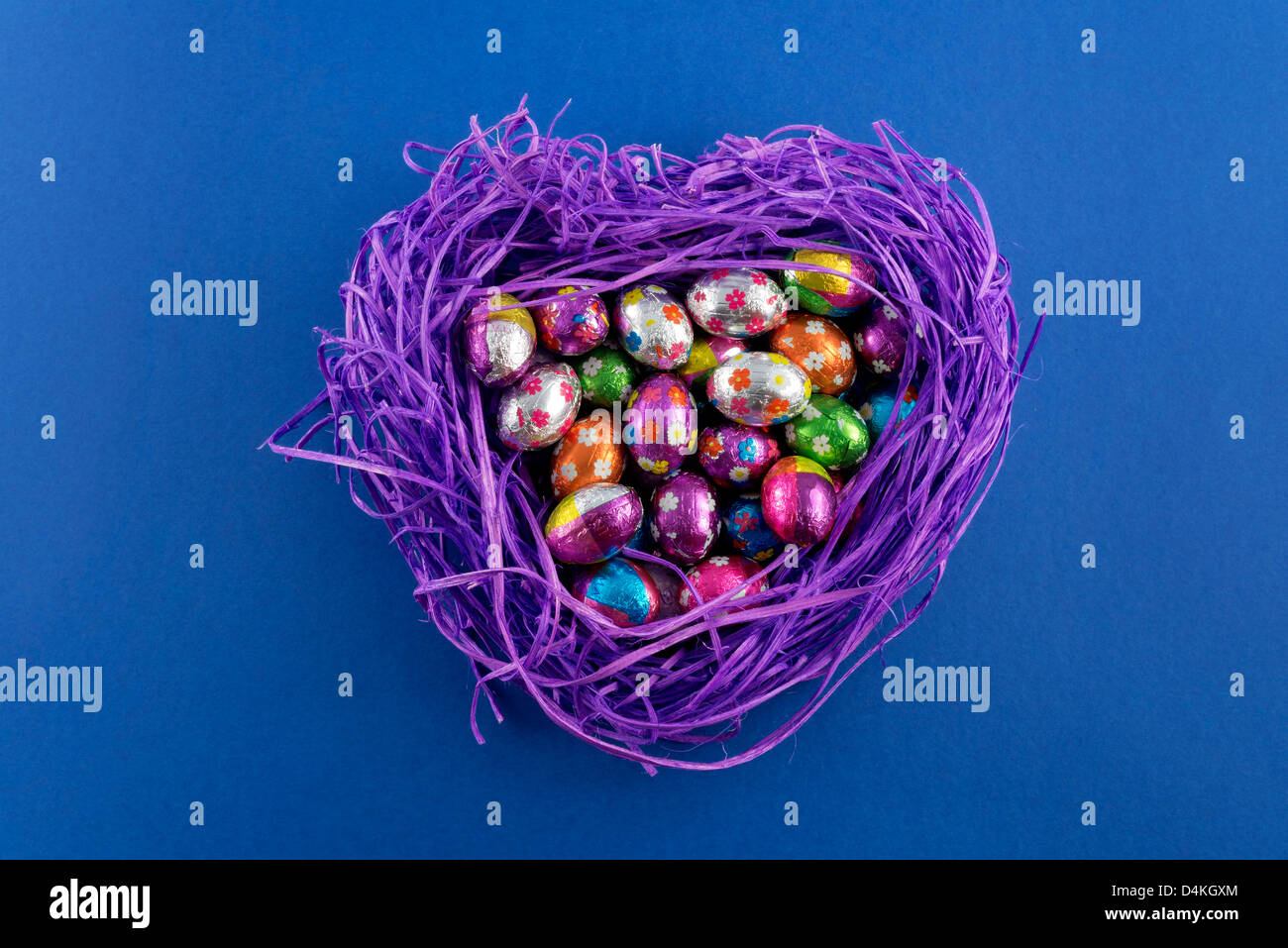 Heart shaped nest with chocolate Easter eggs on blue background Stock ...