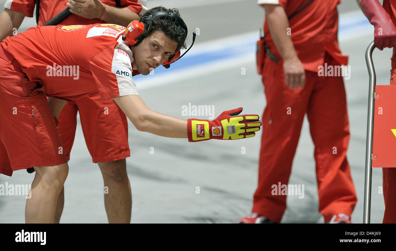 A Ferrari mechanic makes a gesture during a pitstop during the training ...