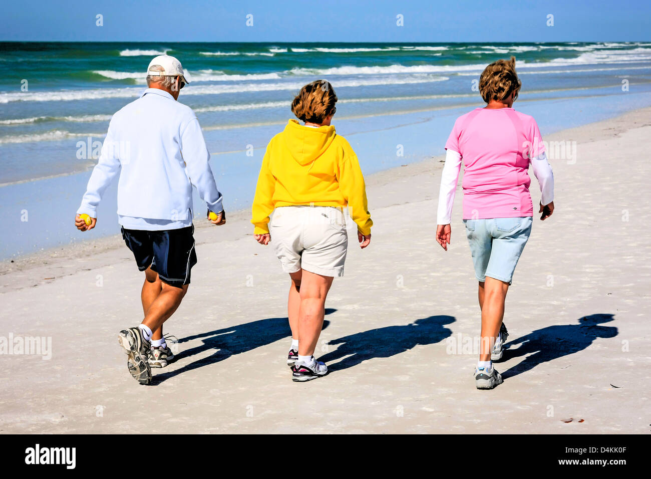 Three retirees on a morning walk along Siesta Key beach in Florida ...