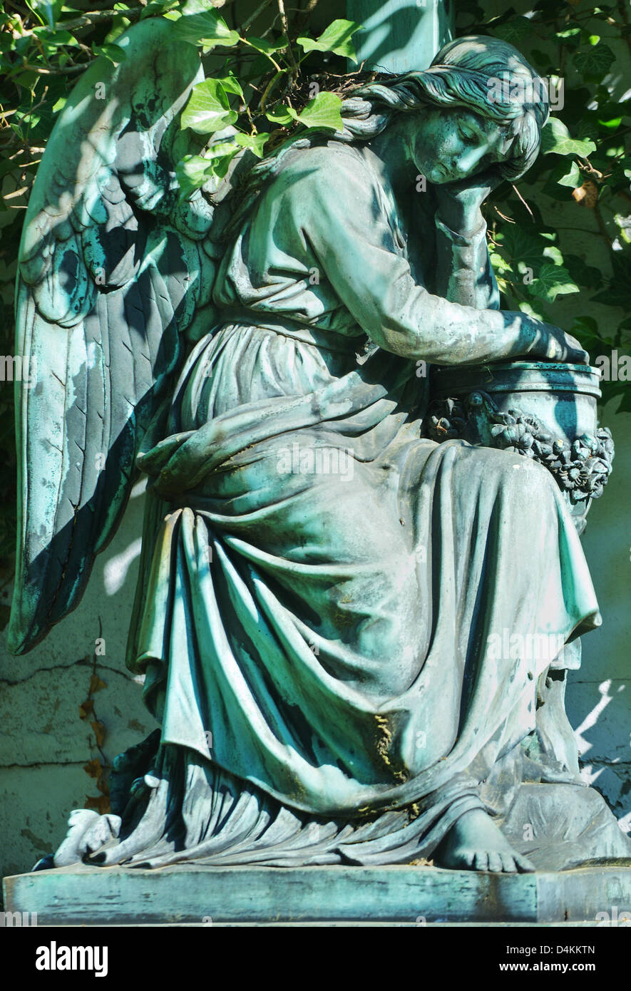 A figure of a female mourning angel, partly overgrown with ivy, is ...