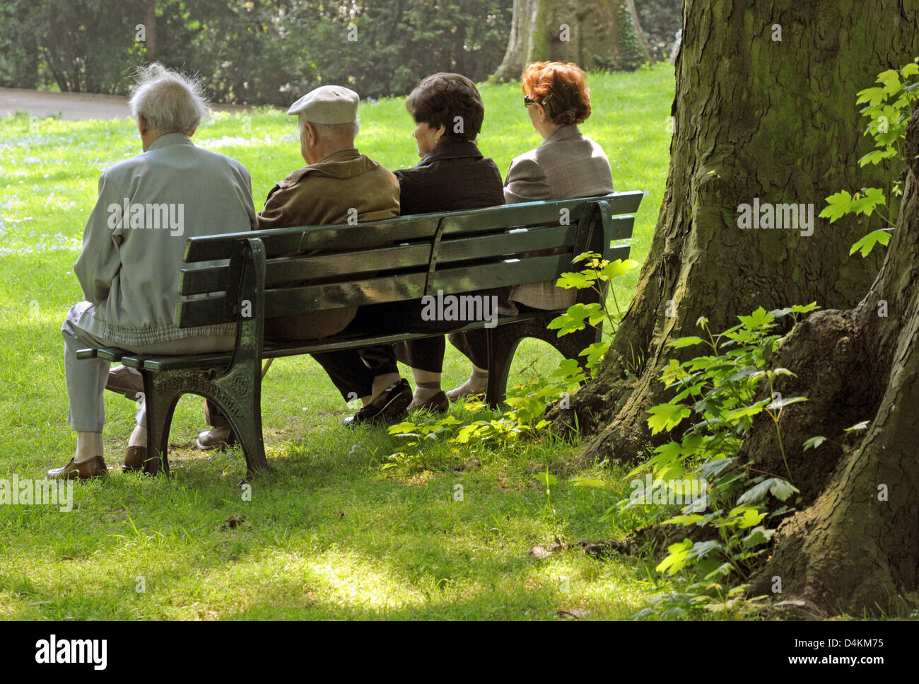 The picture shows senior citizens sitting on a bench in a park in ...