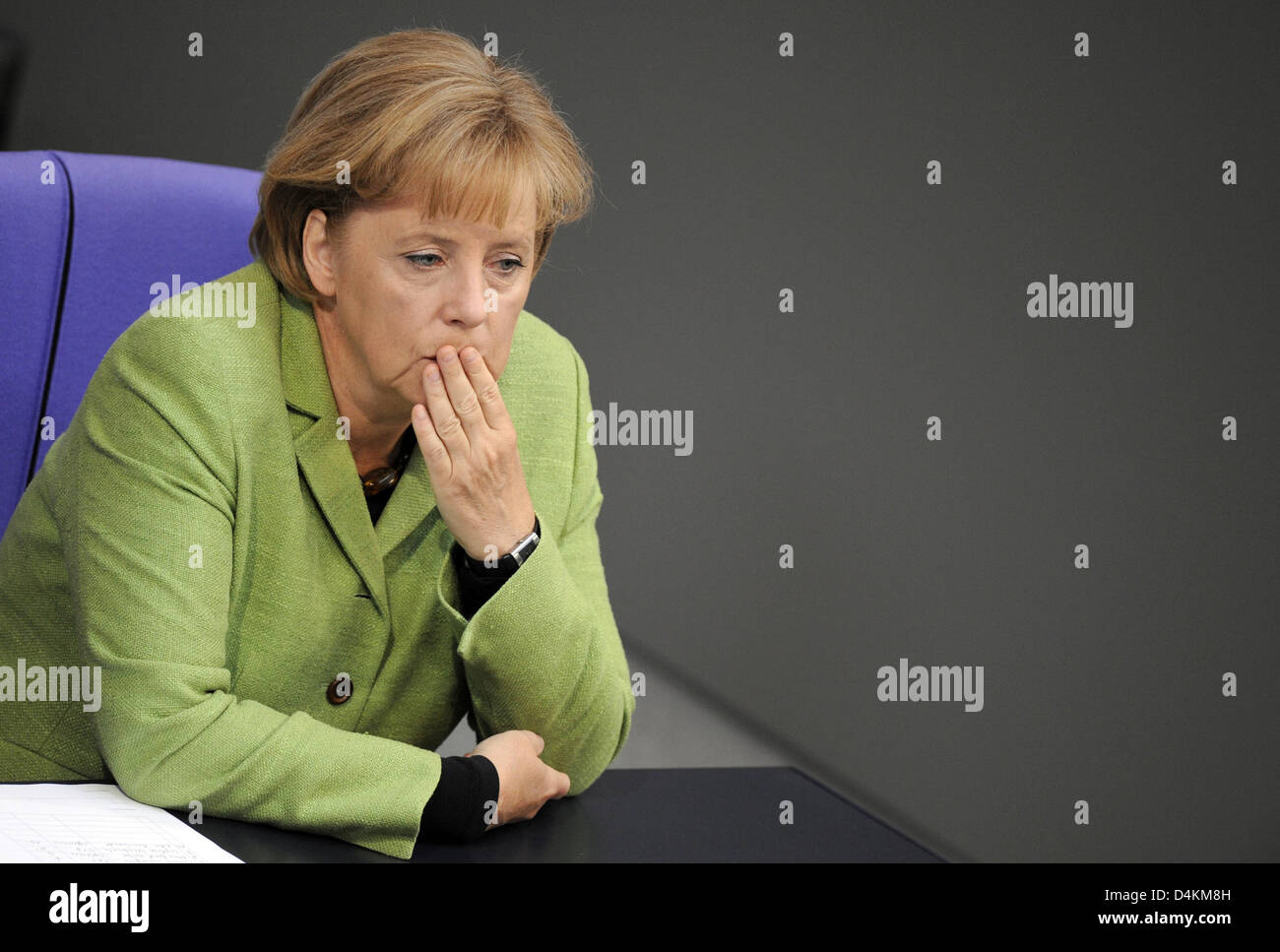 German Chancellor Angela Merkel (CDU) covers her mouth while she sits ...