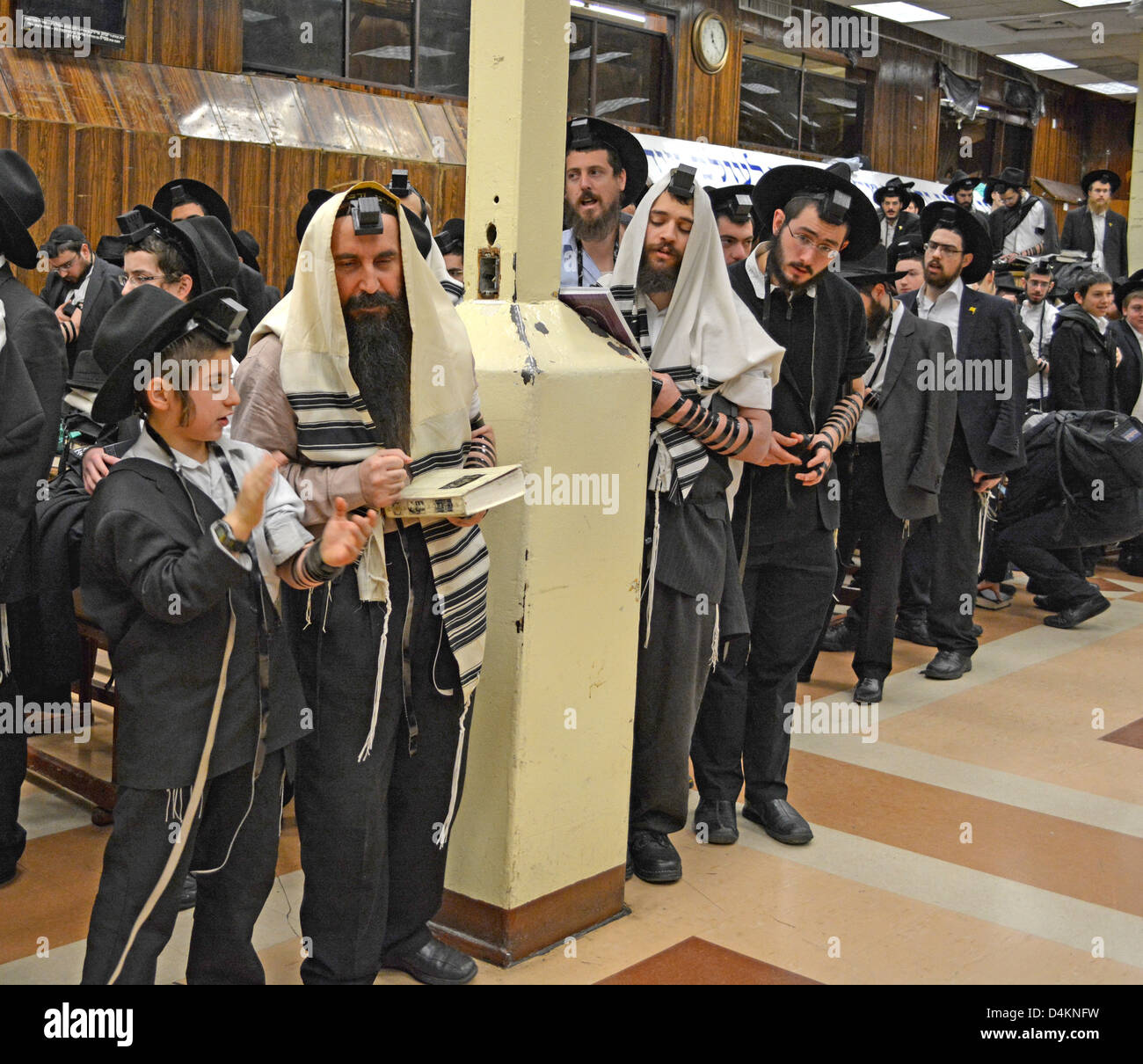 Orthodox Jewish men and a boy at weekday morning prayers wearing scull ...