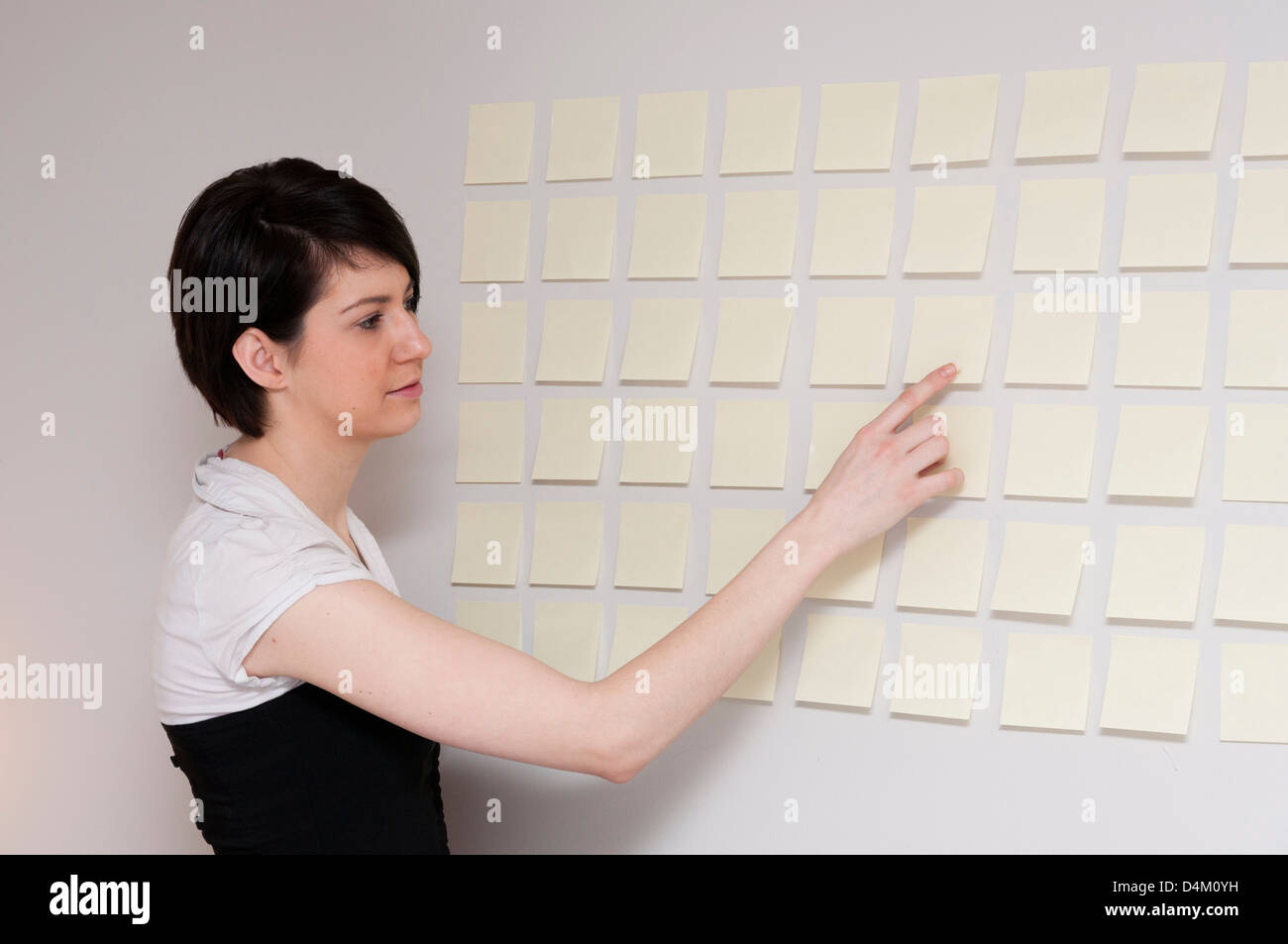 Young woman next to wall of sticky paper post-it notes Stock Photo - Alamy