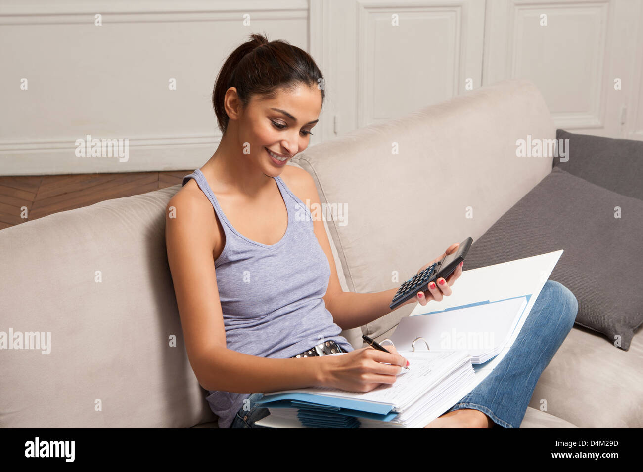 Woman doing homework on sofa Stock Photo - Alamy