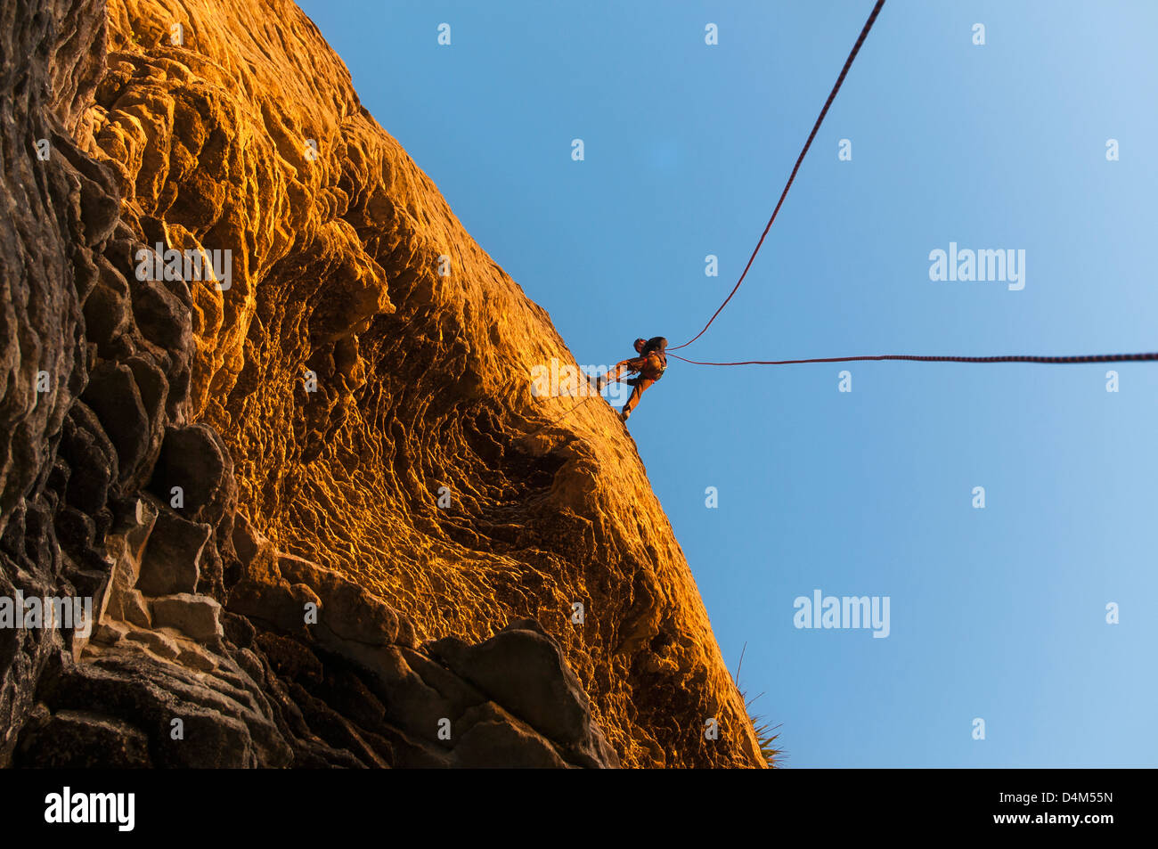 Rock climber scaling steep rock face Stock Photo - Alamy