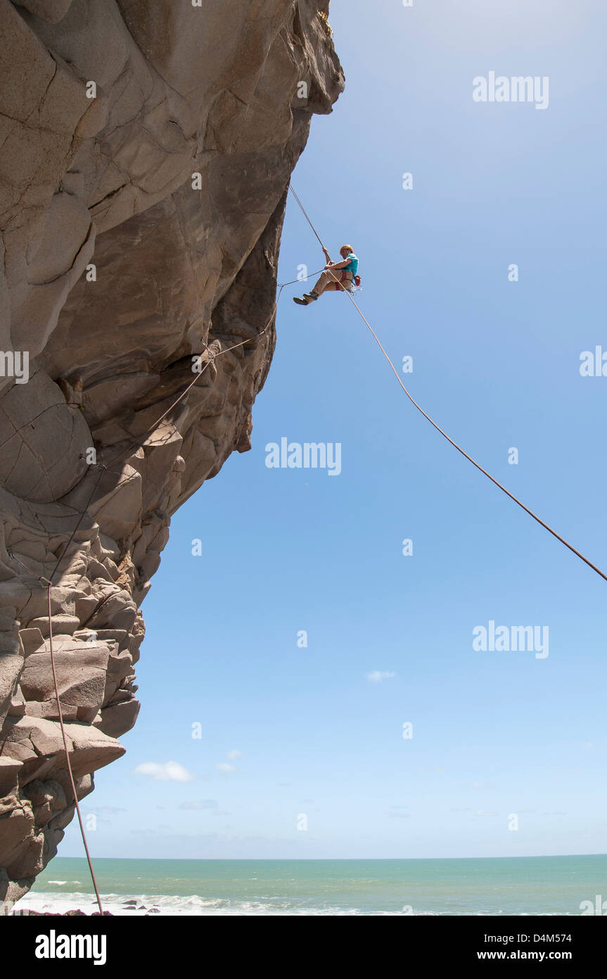 Rock climber abseiling jagged cliff Stock Photo - Alamy