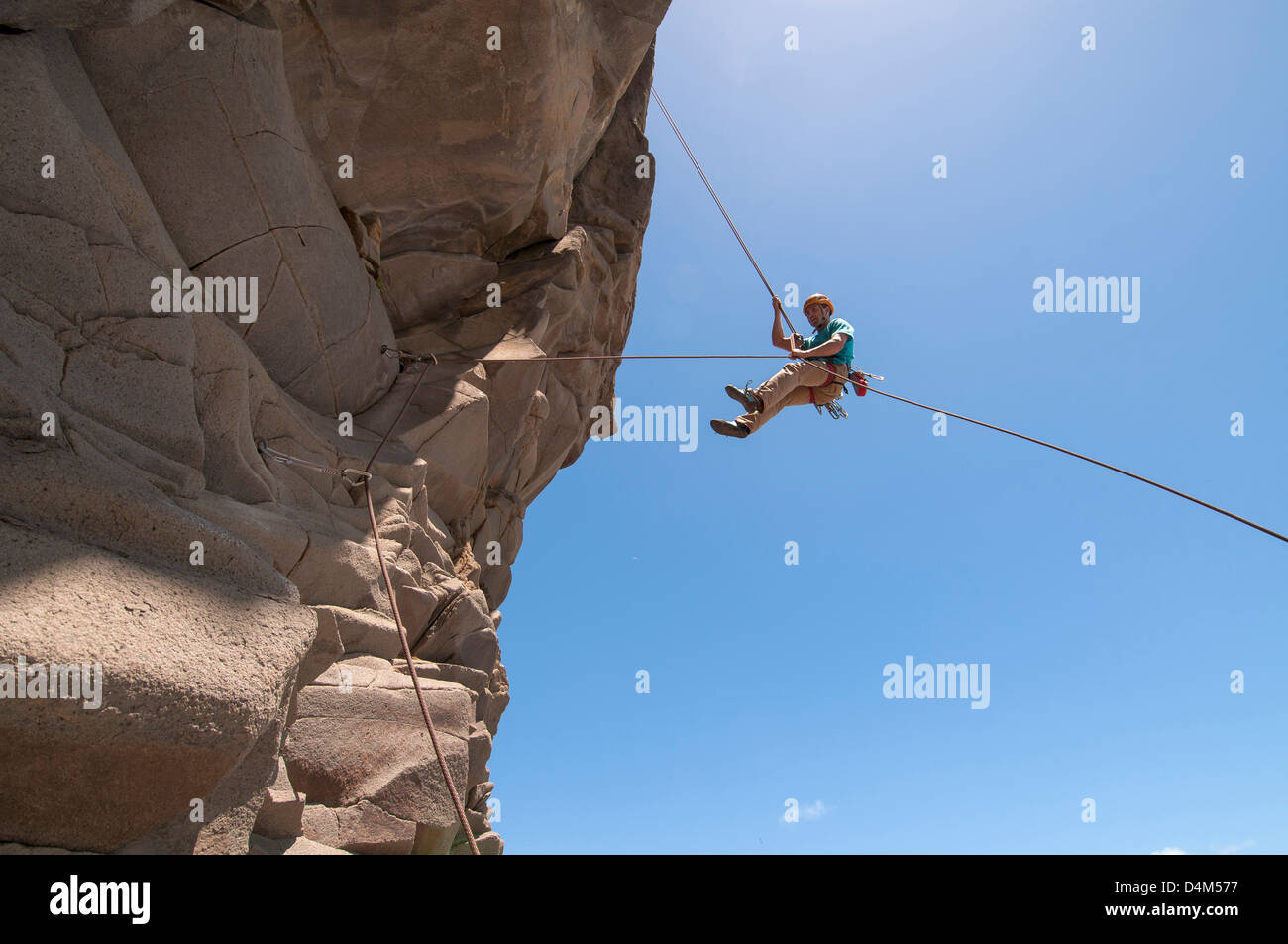 Rock climber abseiling jagged cliff Stock Photo - Alamy