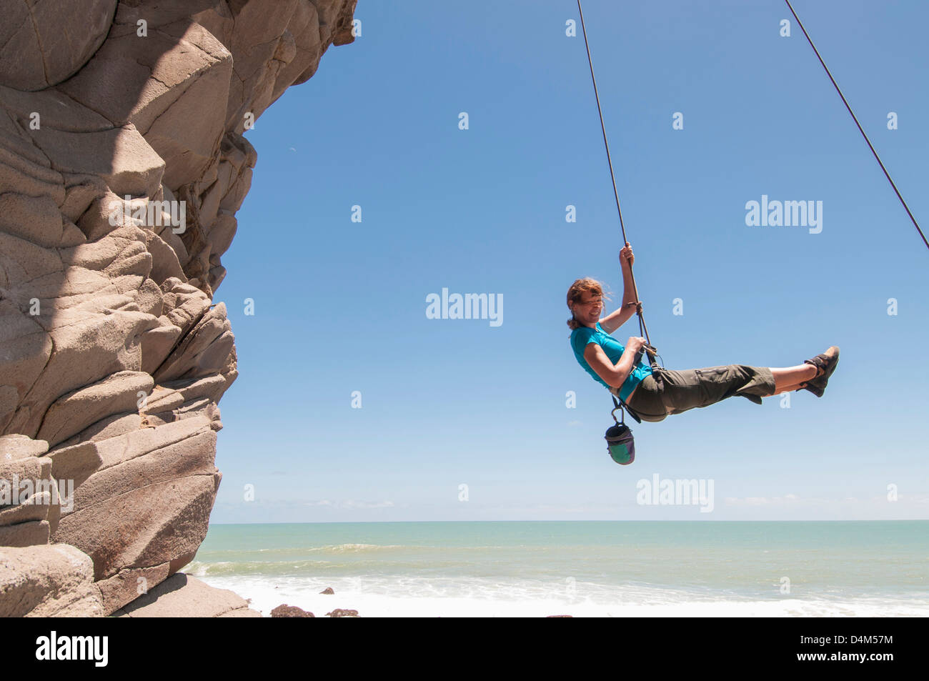 Rock climber abseiling jagged cliff Stock Photo - Alamy