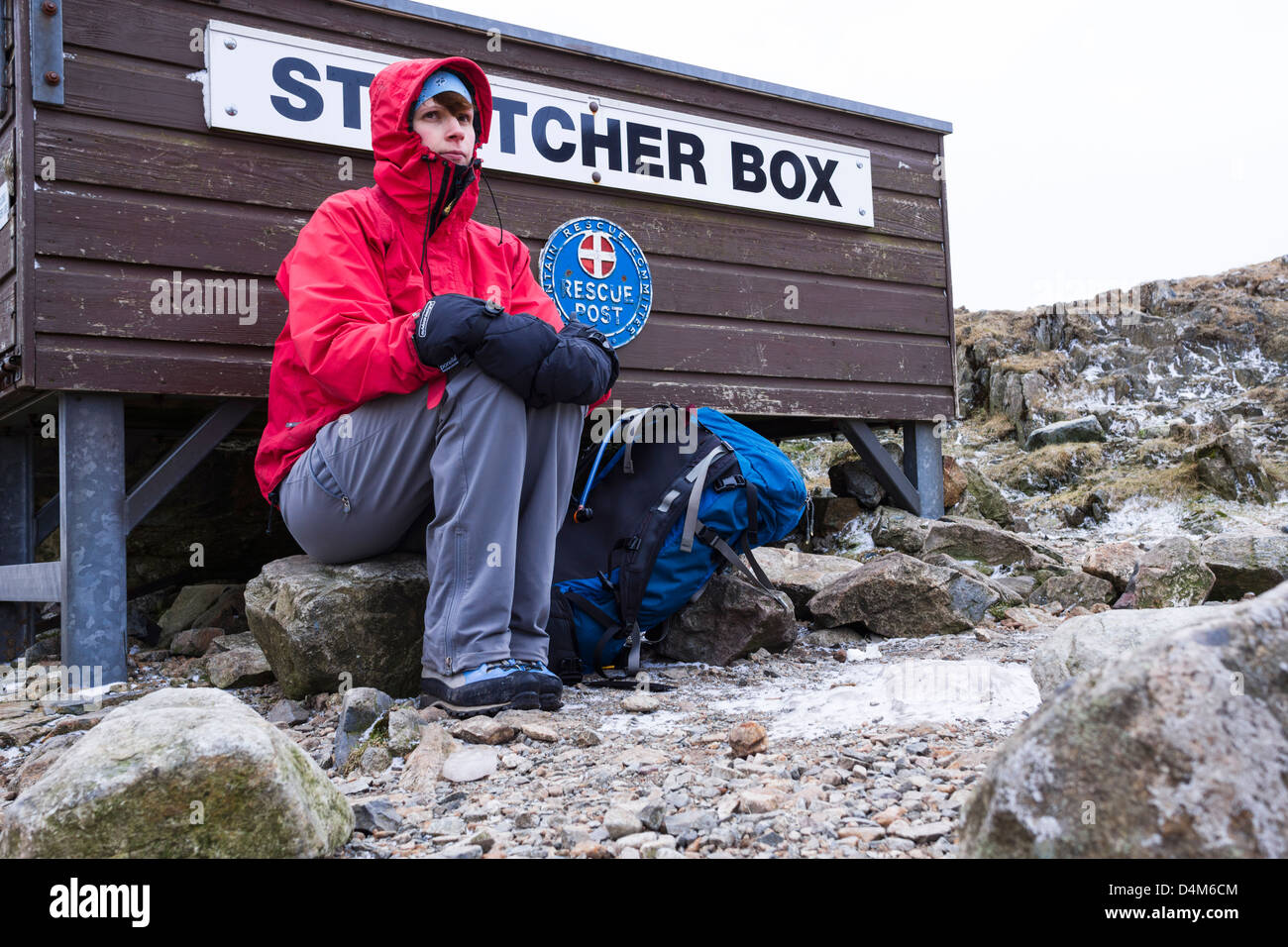 A hiker waiting by a Stretcher box, Rescue Post in the Lake District ...
