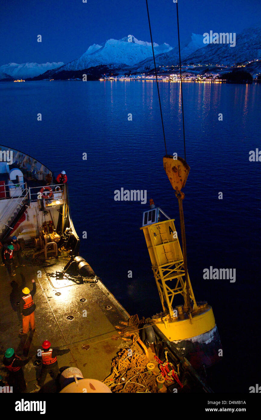 A buoy marking a safe navigational route is illuminated at night to ...