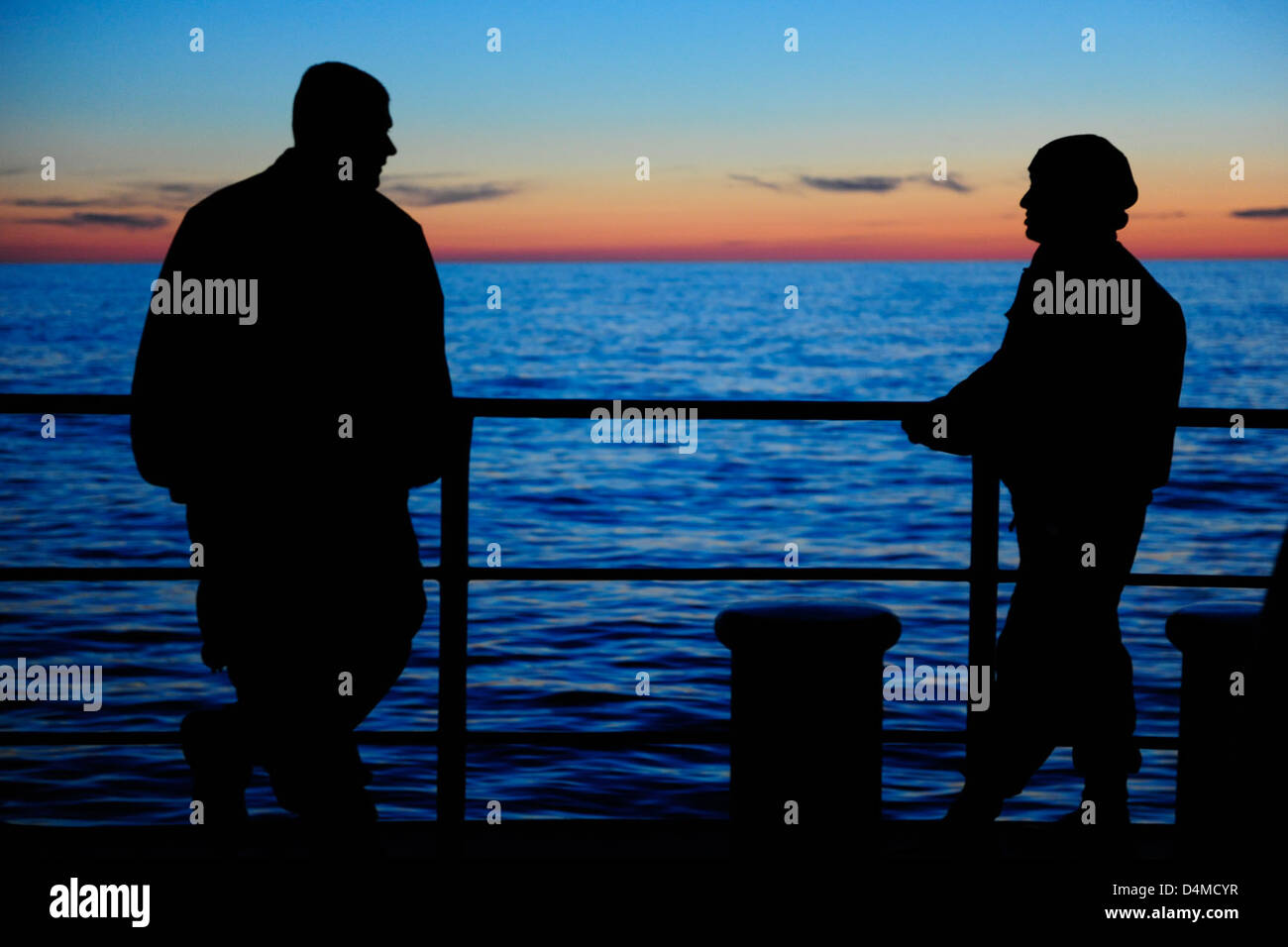 A Coast Guard ship passes into the horizon during sunset while underway ...