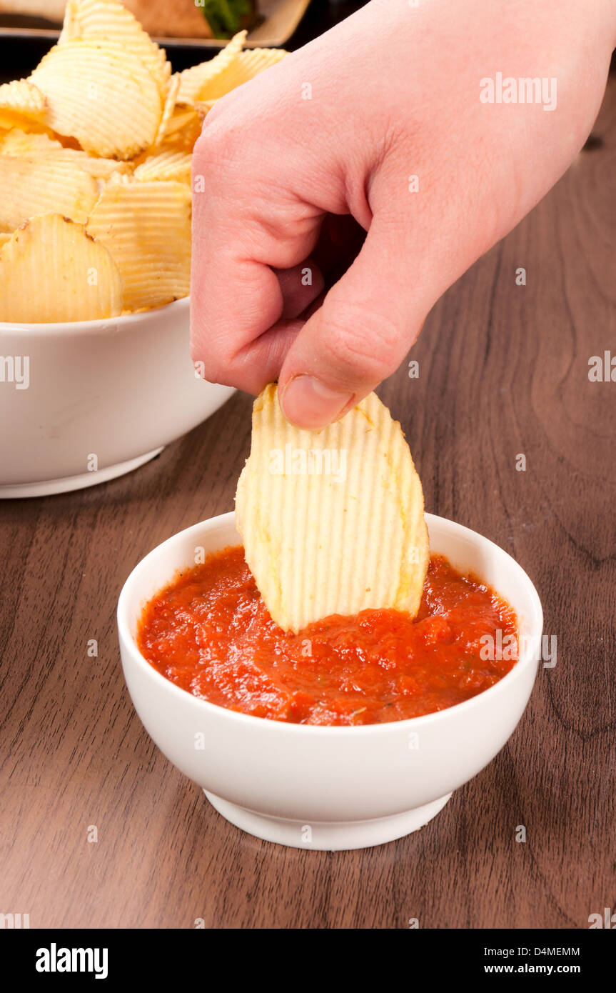 Hand dipper potato chips in the salsa sauce Stock Photo - Alamy
