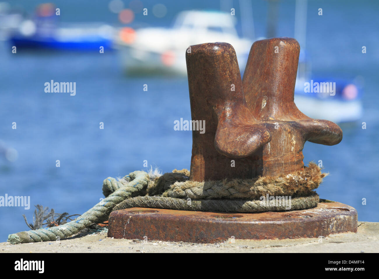 A heavy metal iron steel mooring cleat with a boat yacht dingy tied up ...