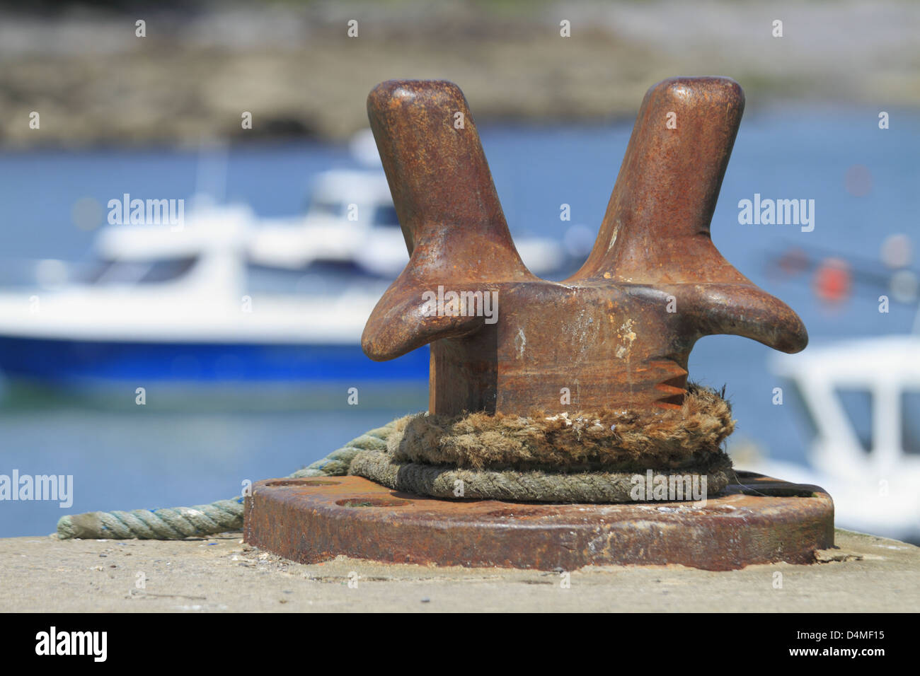 A heavy metal iron steel mooring cleat with a boat yacht dingy tied up ...