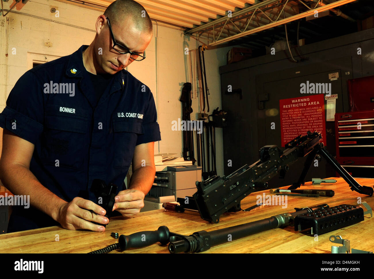 A Coast Guard Gunners Mate performs maintenance on a M240 machine gun ...