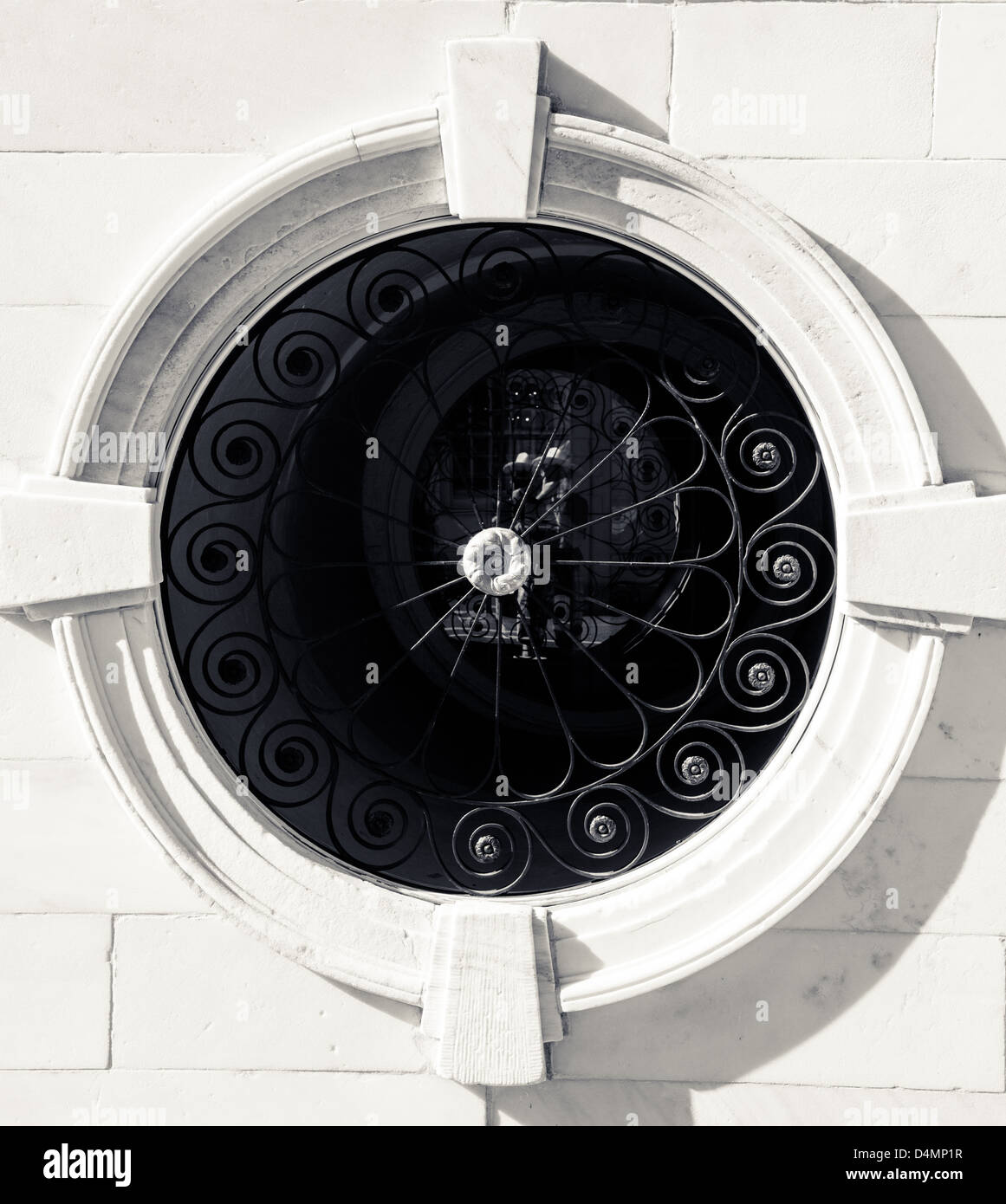 A round window with iron work detail and the reflection of the ...
