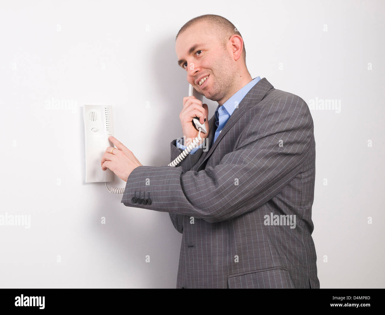 Businessman pressing an intercom with a smile and positive attitude on ...