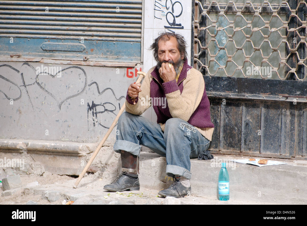 An elderly homeless man eating on the street, Bucharest, Romania ...