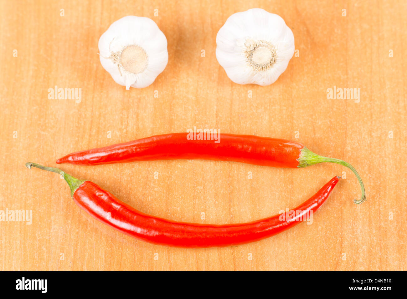 Smiley face made of garlic and chili pepper, on wooden background, high ...