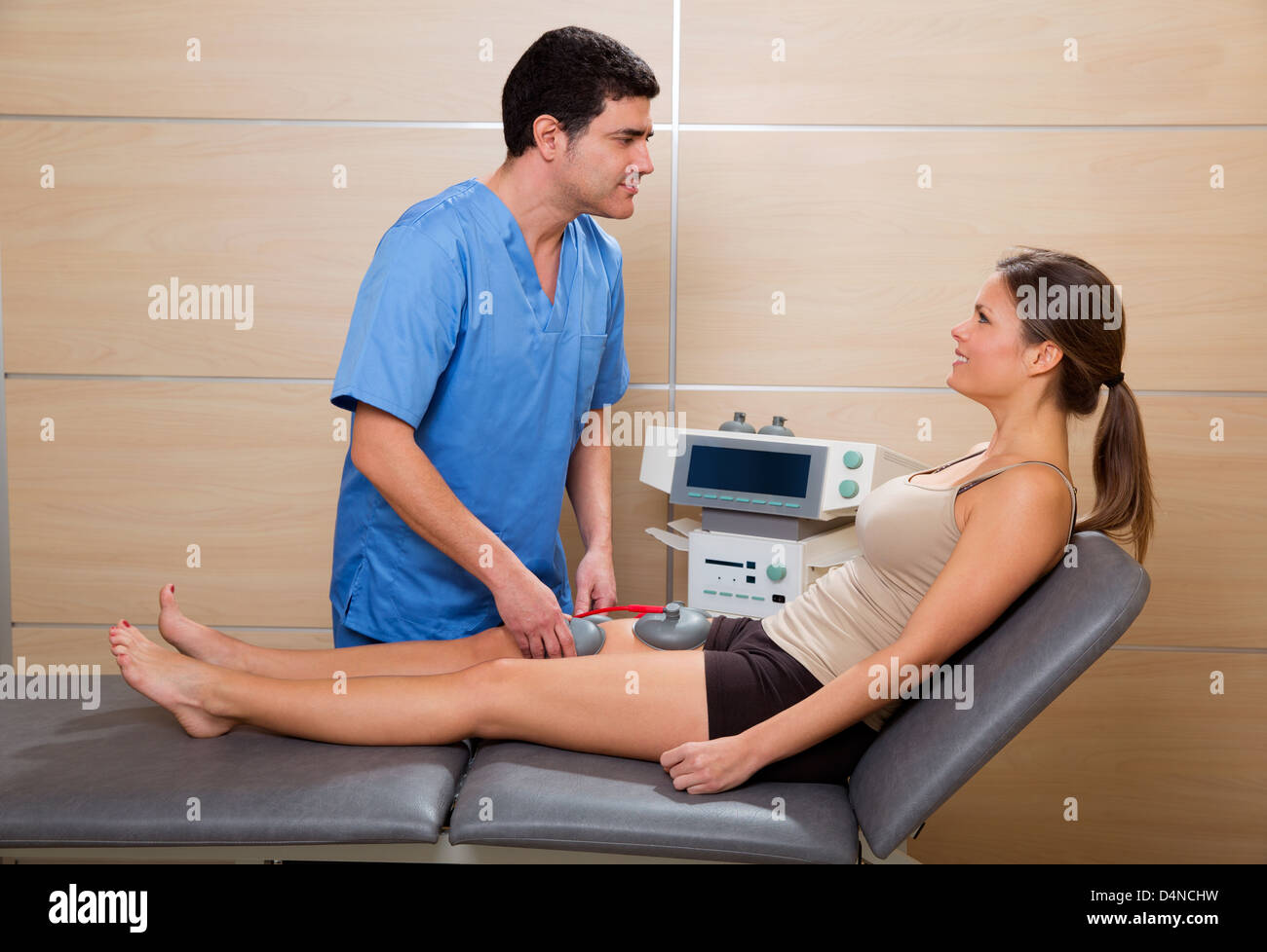 Doctor therapist checking leg muscle electrostimulation to woman ...