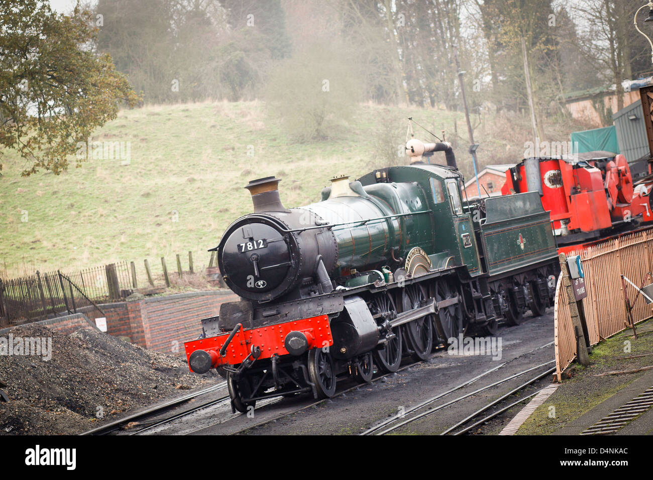 A dark green and black steam engine or locomotive in a rural setting ...
