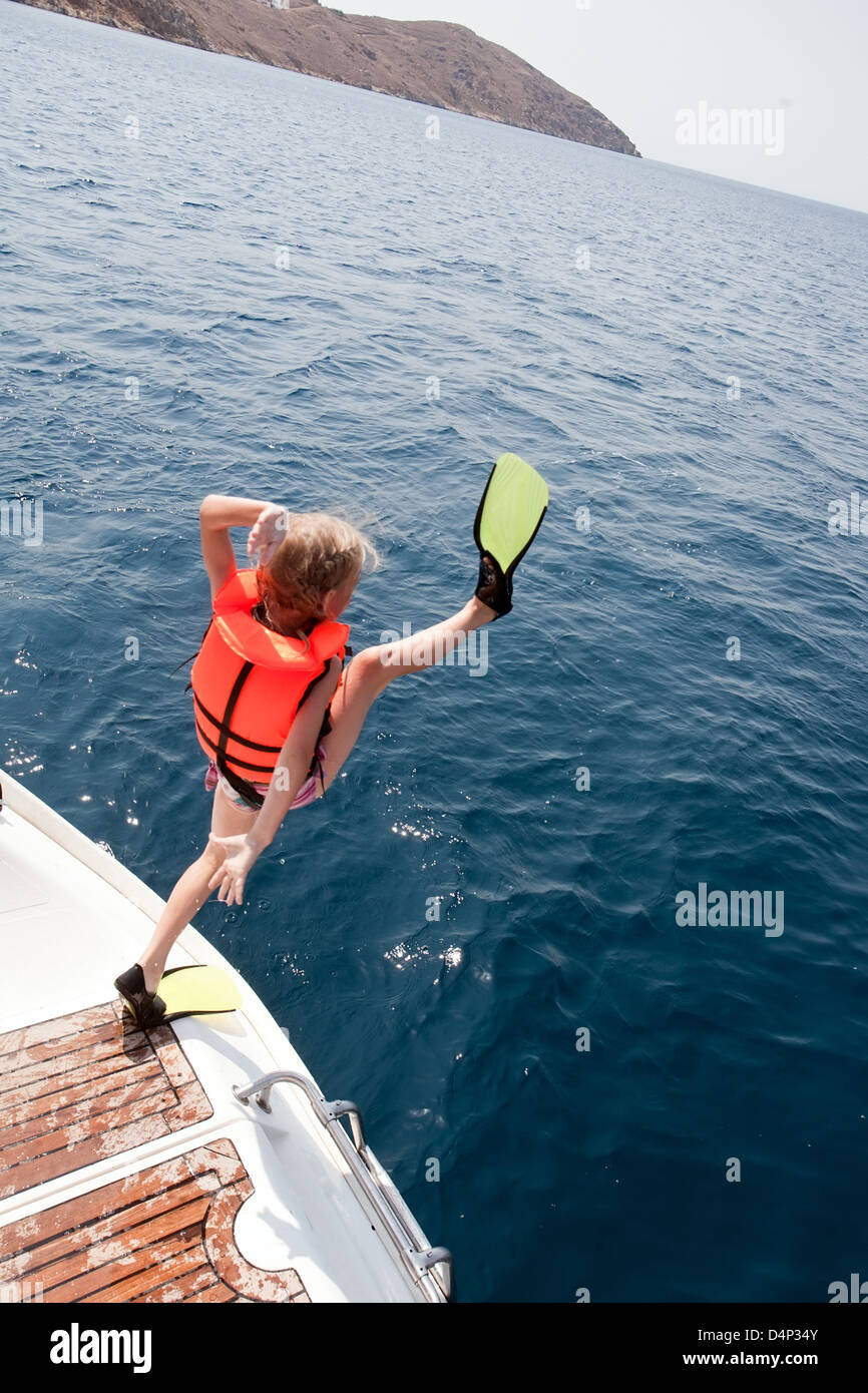 little girl in life jacket and flippers jumping to sea water from yacht ...