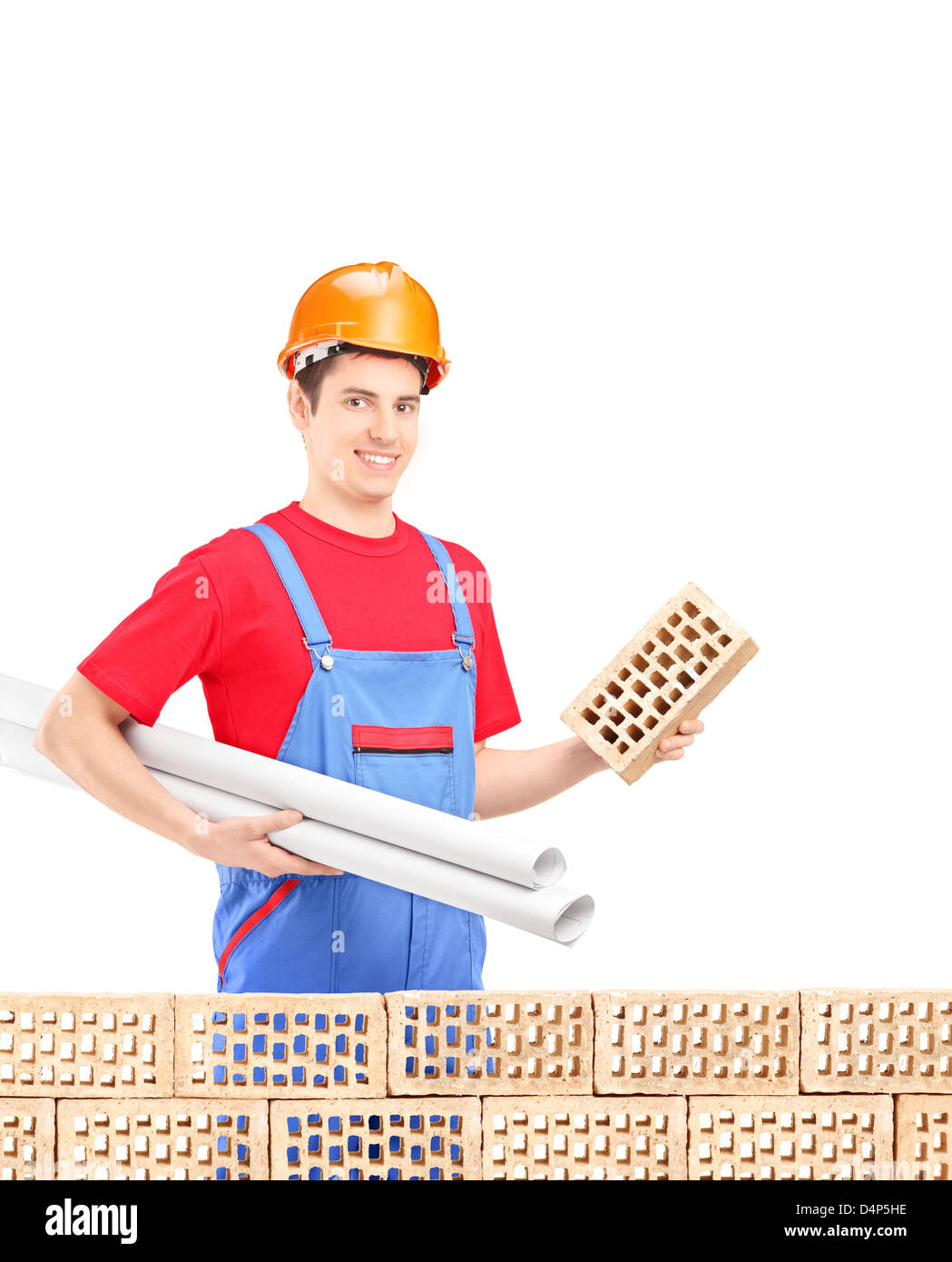 Male engineer with helmet holding a brick and blueprints behind a wall ...