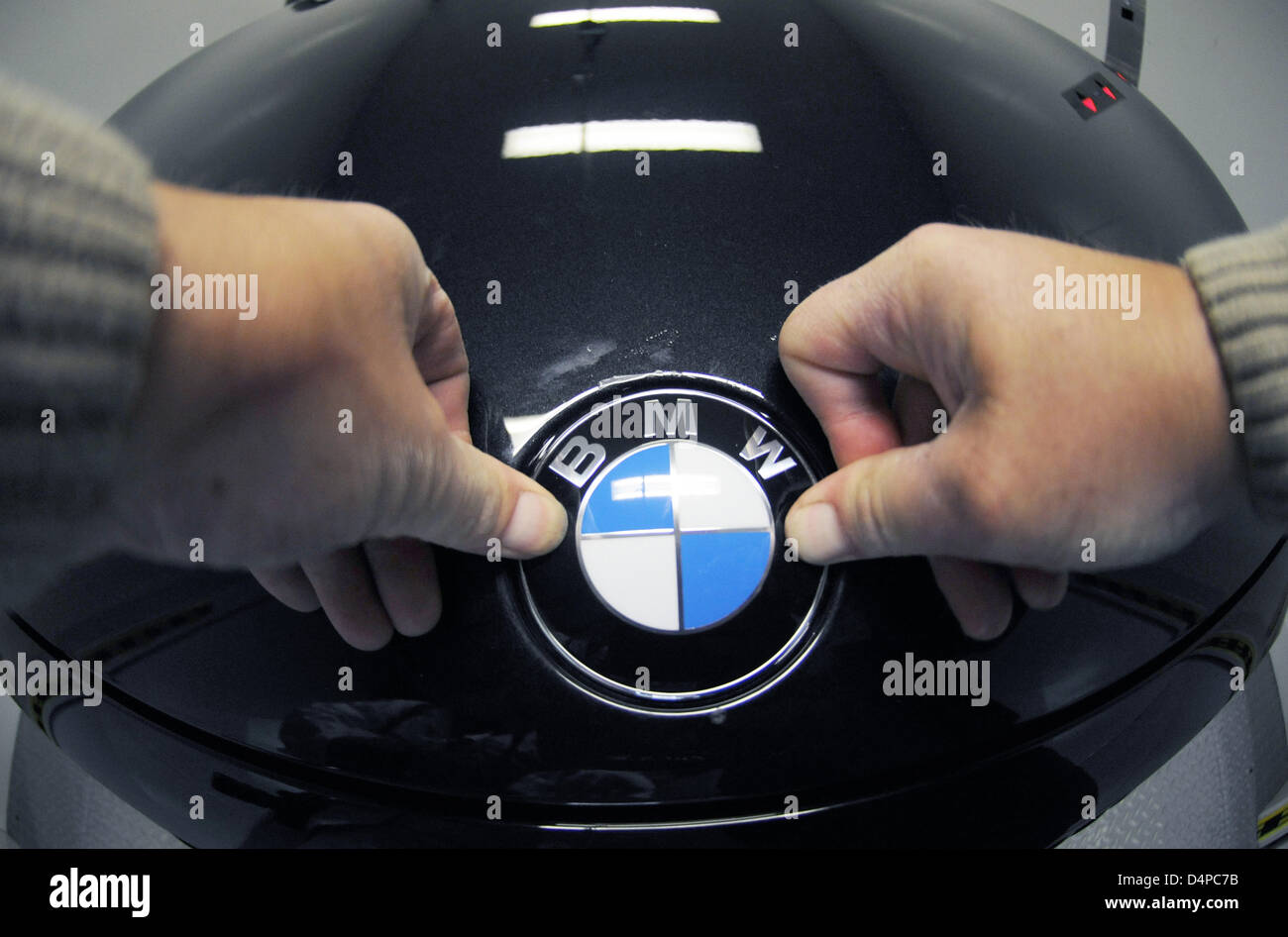A worker attaches a BMW emblem to a car at the company?s production ...