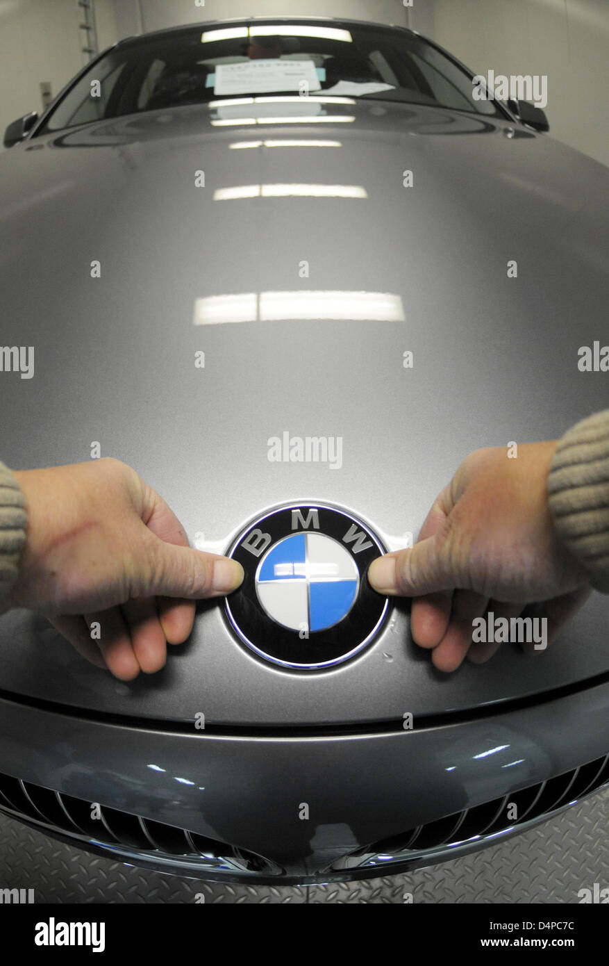 A worker attaches a BMW emblem to a car at the company?s production ...