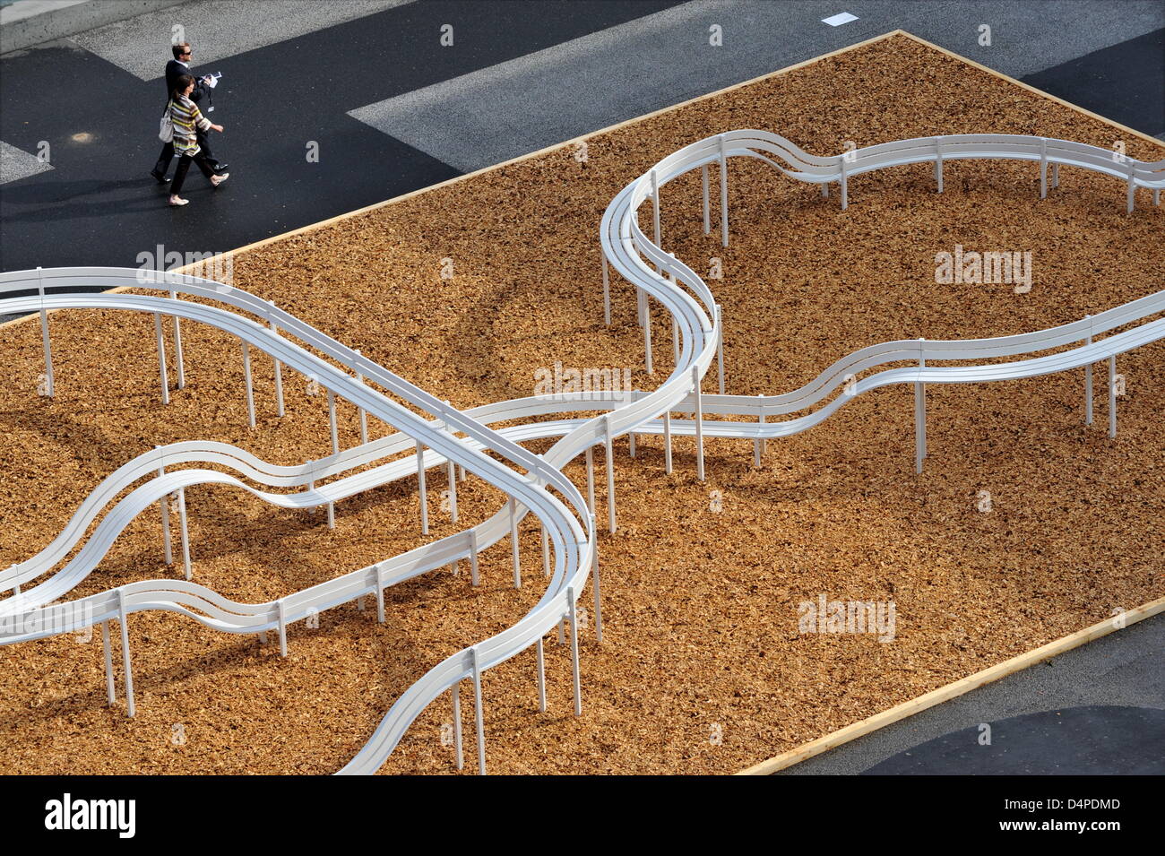 Two people pass the sculpture ?Loop Bench? by Danish artist Jeppe Hein ...