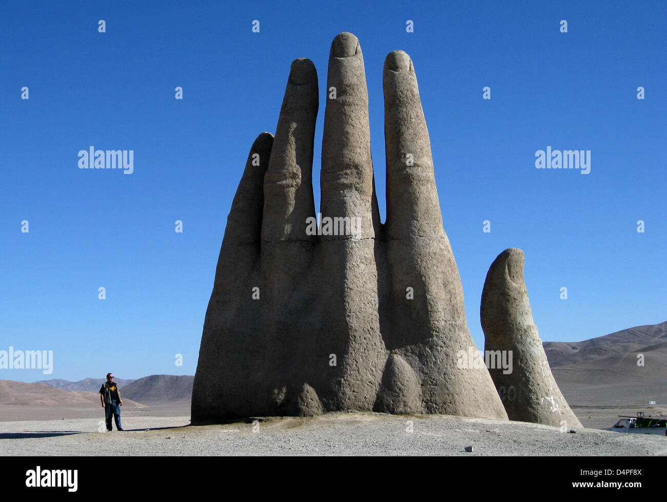 A man stands next to the concrete sculpture ?Mano del Desierto? (?Hand ...