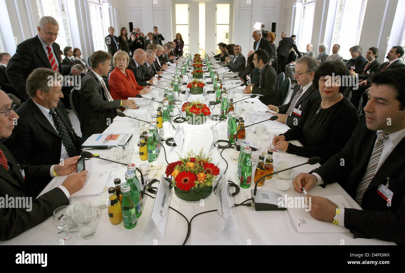 Participants of the 4th German Islam Conference sit on a table in ...