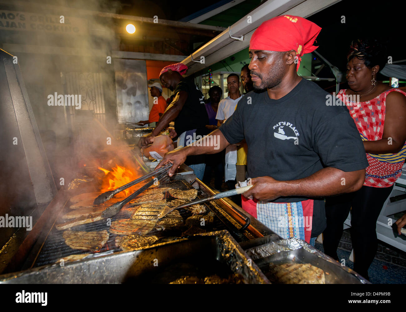 A man frying up fish on a BBQ at Oistins fish fry night, Oistins ...